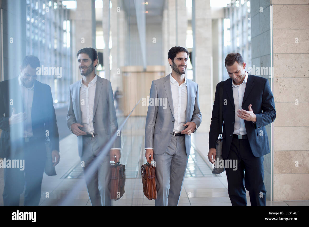 Two young businessmen walking and chatting in conference centre Stock ...