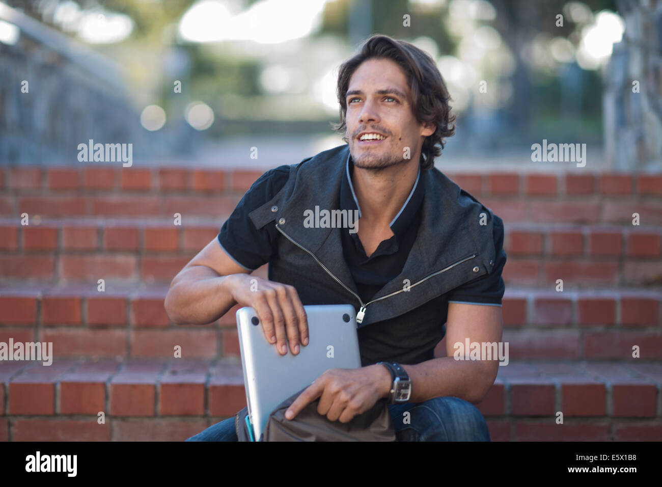 Mid adult man taking laptop from rucksack on city steps Stock Photo - Alamy