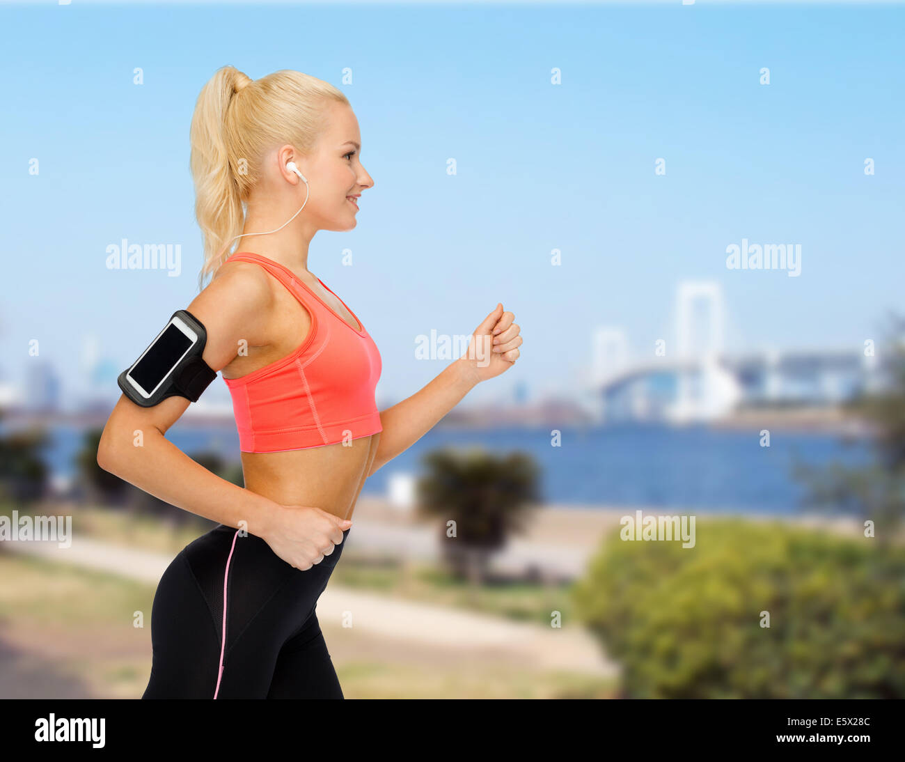sporty woman running with smartphone and earphones Stock Photo - Alamy