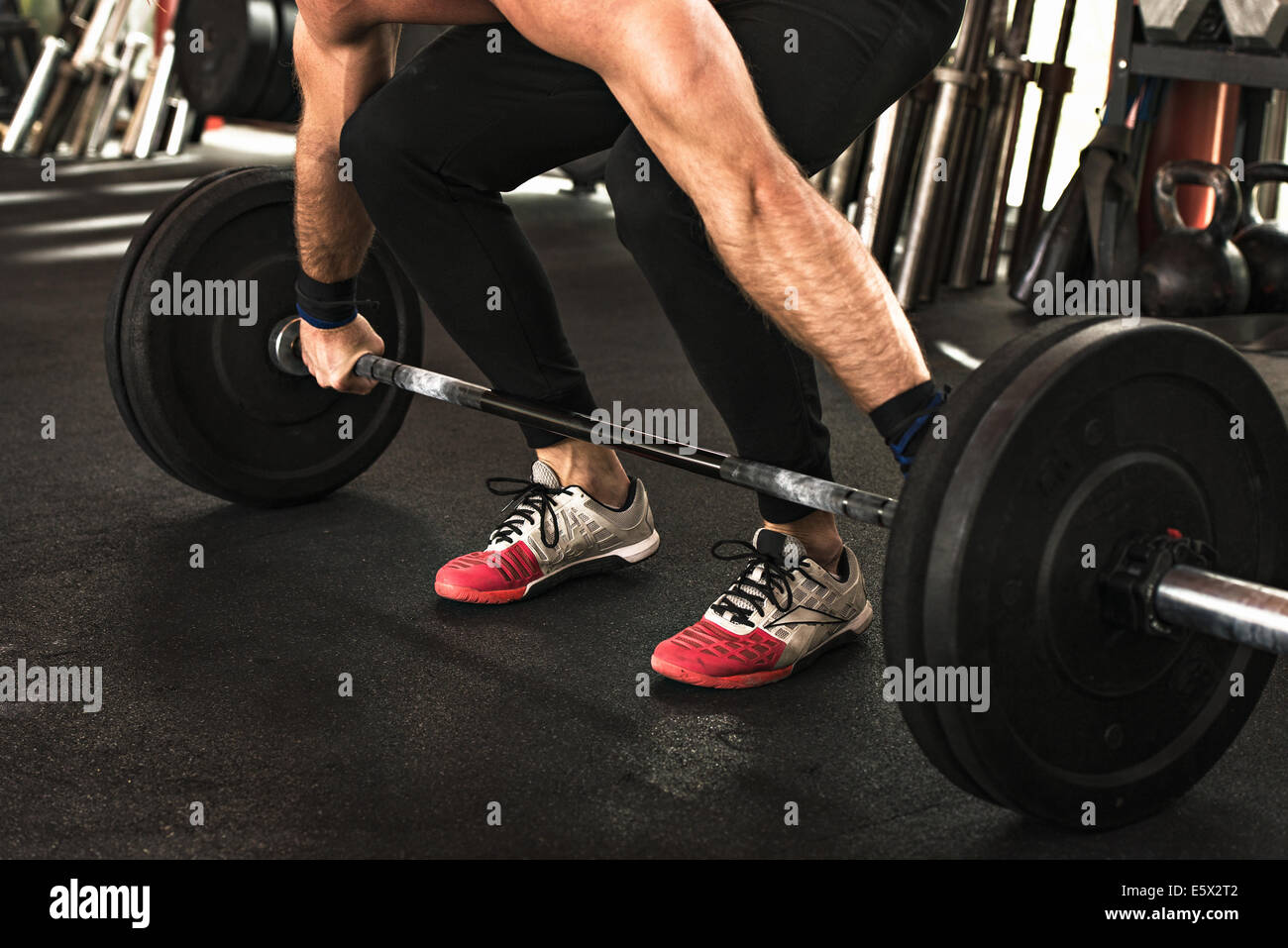 Bodybuilder bending to lift barbell in gym Stock Photo - Alamy