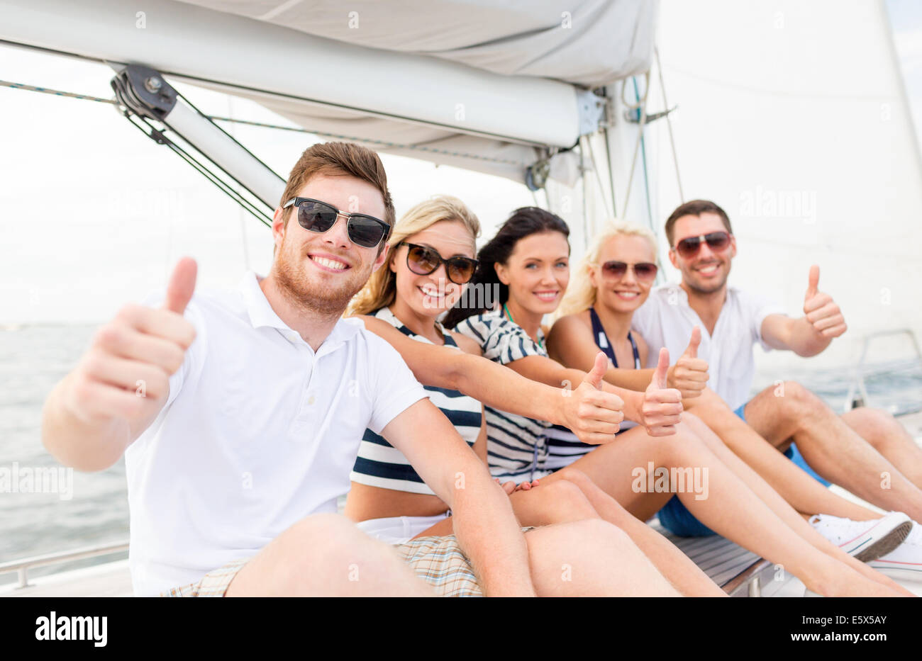 smiling friends on yacht showing thumbs up Stock Photo - Alamy