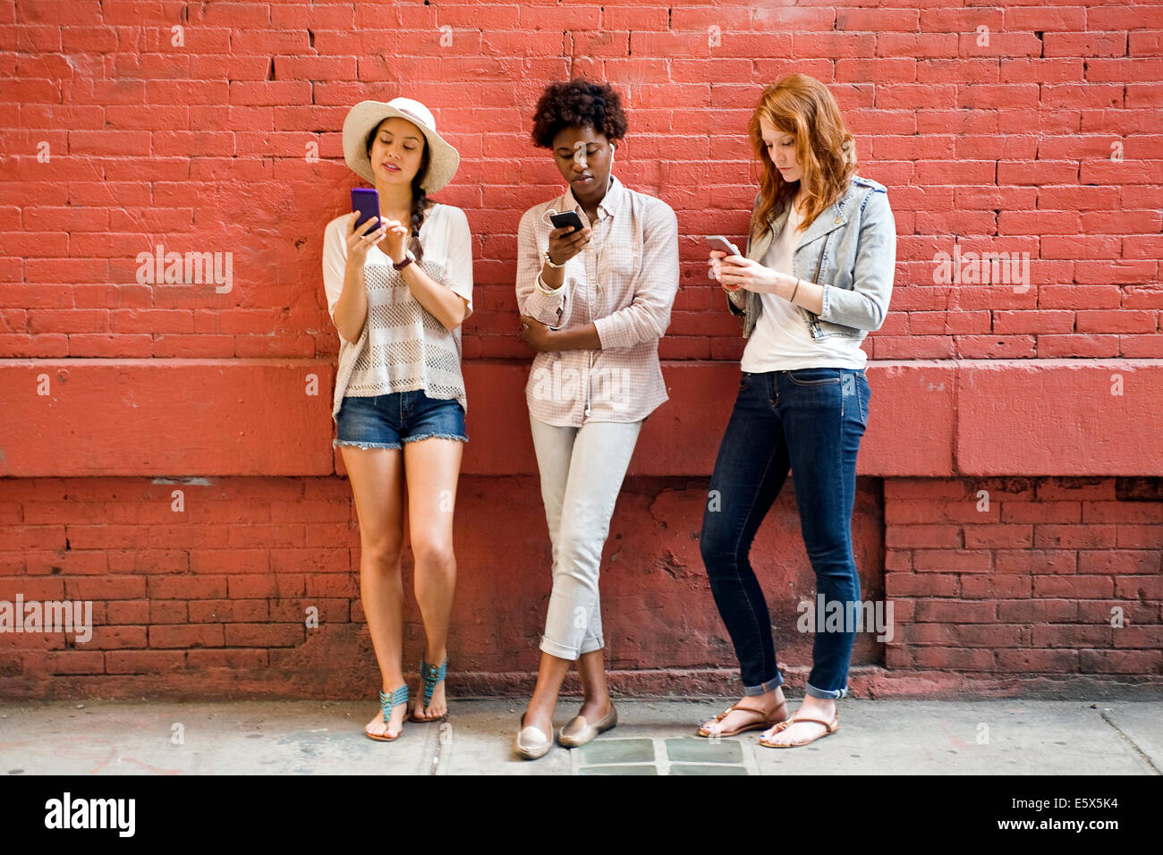 Portrait of three young women using mobile phones Stock Photo - Alamy