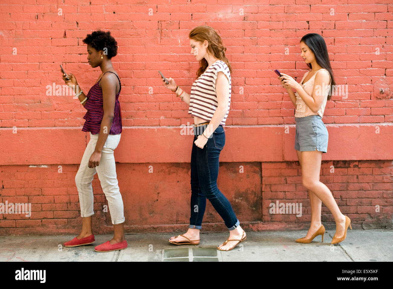 Portrait of three young women using mobile phones Stock Photo - Alamy