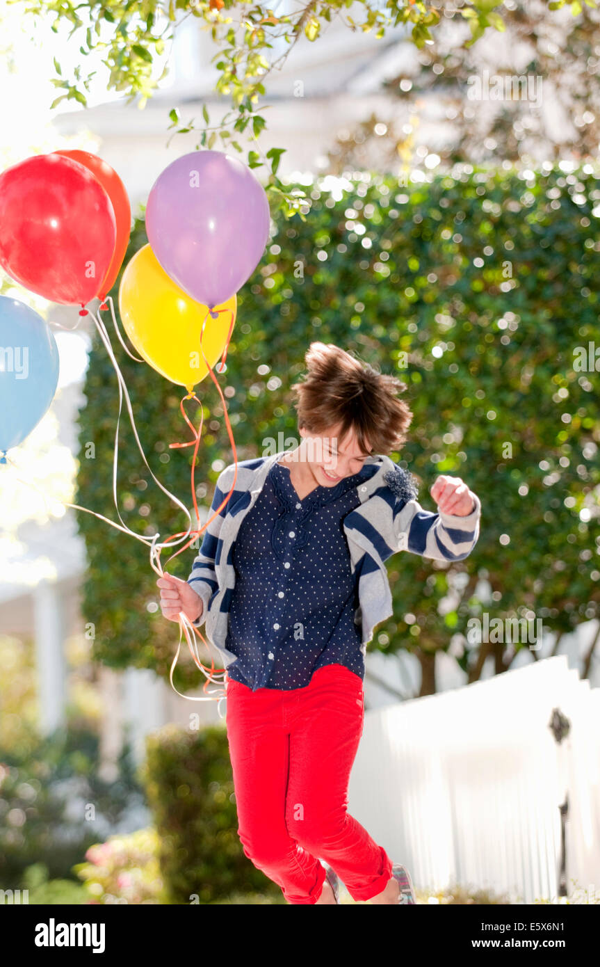 Ten year old girl jumping excitedly with bunch of balloons Stock Photo ...
