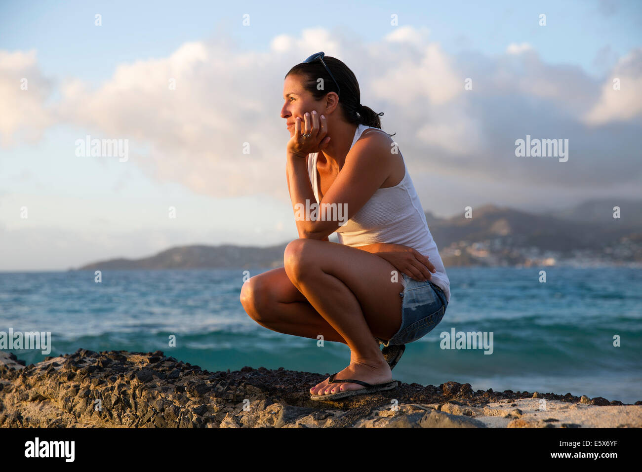 Mid Adult Woman Crouching And Gazing At Caribbean Sea From Pier Spice