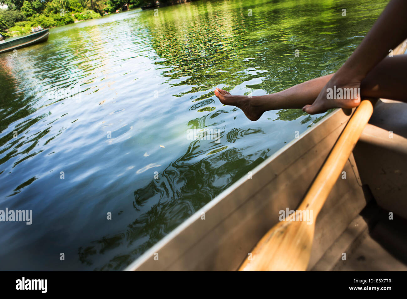 Cropped image of young woman's legs in rowing boat on lake in Central ...