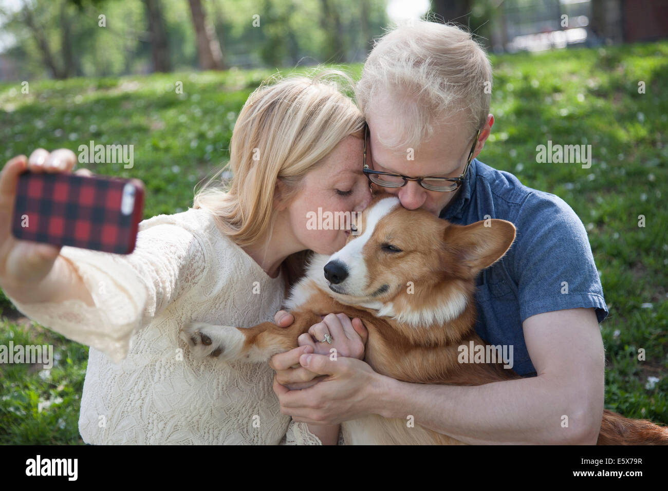 Young couple in park taking selfie whilst kissing corgi dog Stock Photo ...