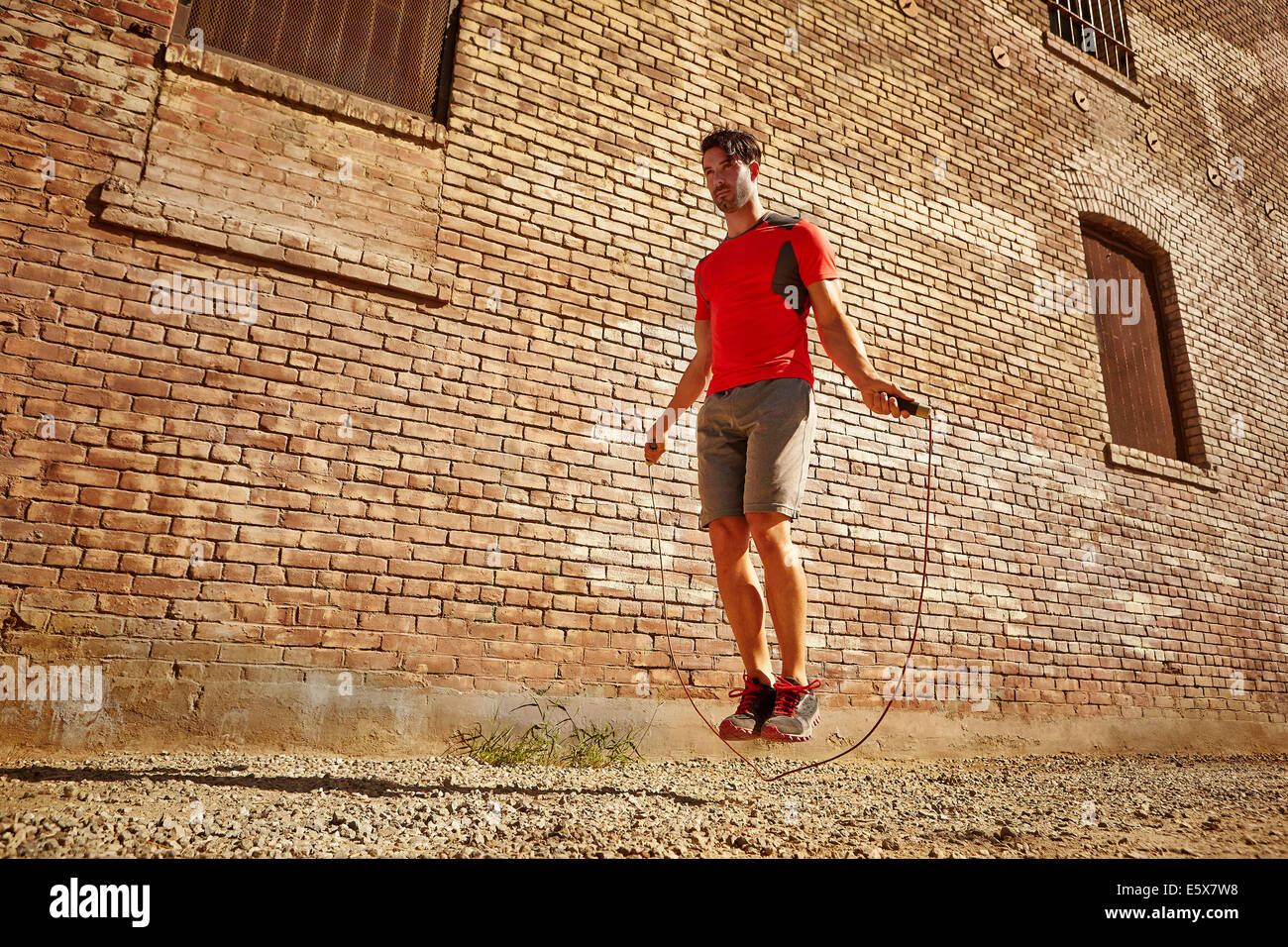 Young man exercising with skipping rope on wasteland Stock Photo - Alamy
