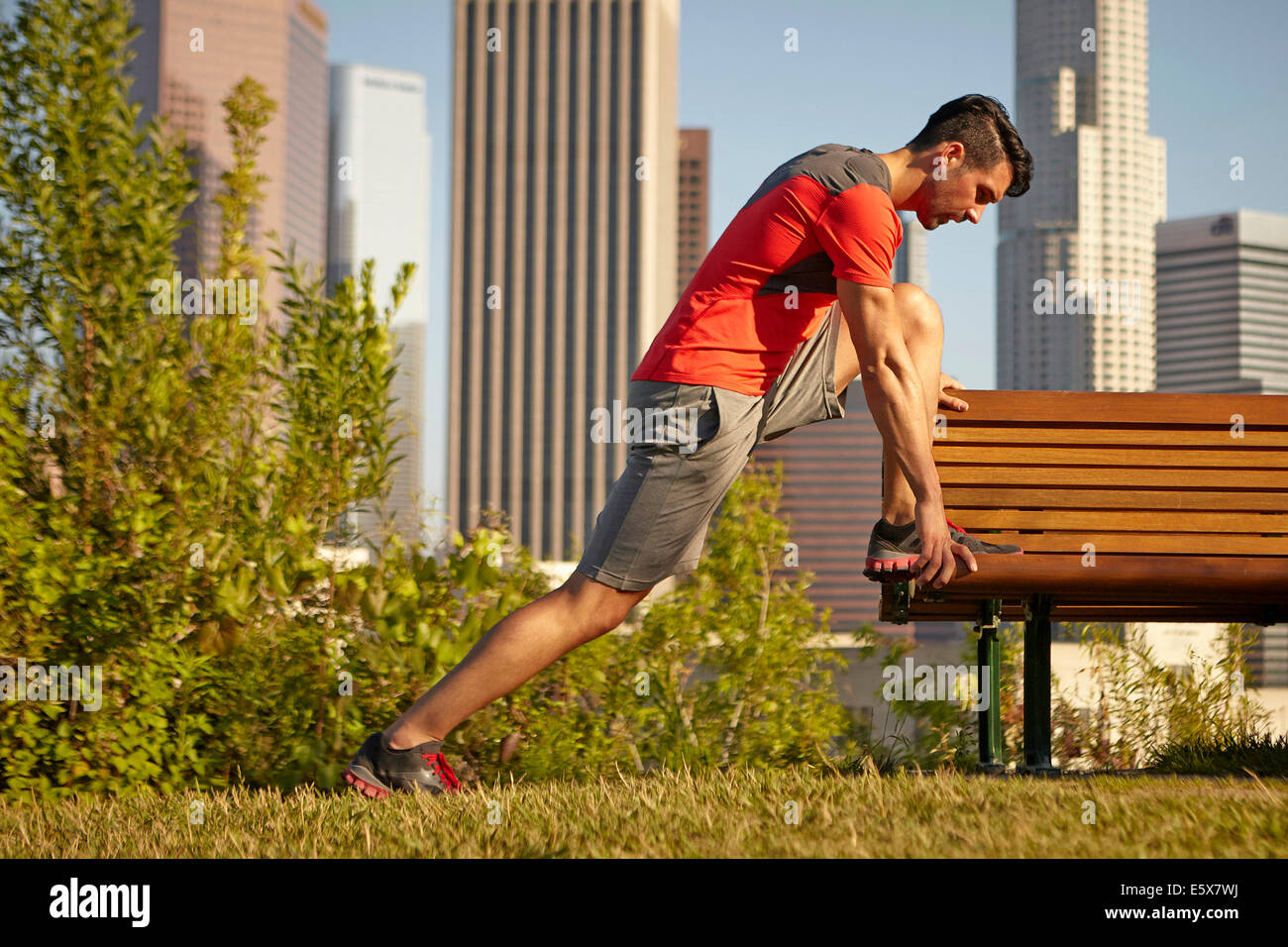Young male runner stretching on park bench Stock Photo - Alamy