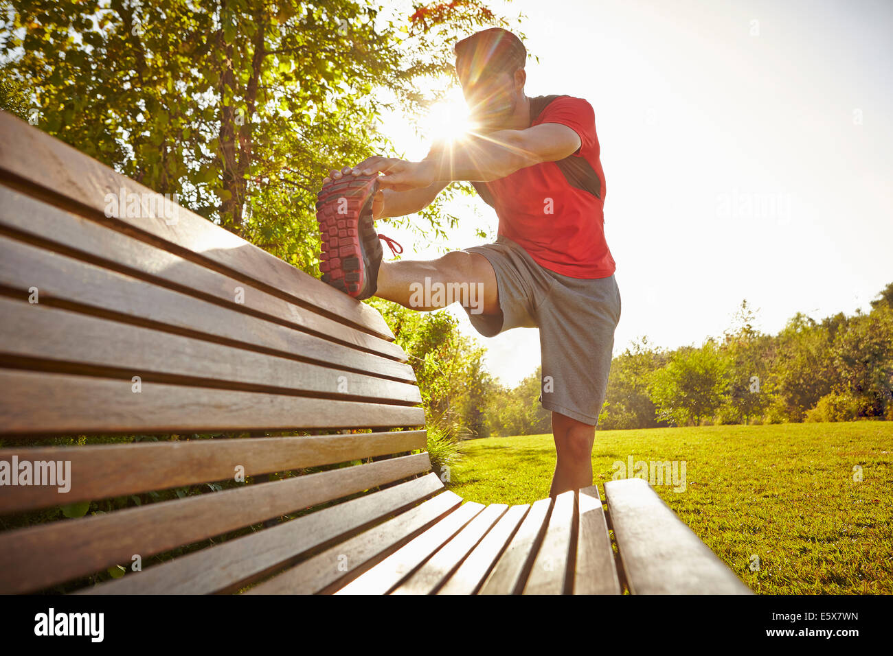 Young male runner stretching legs on park bench Stock Photo - Alamy