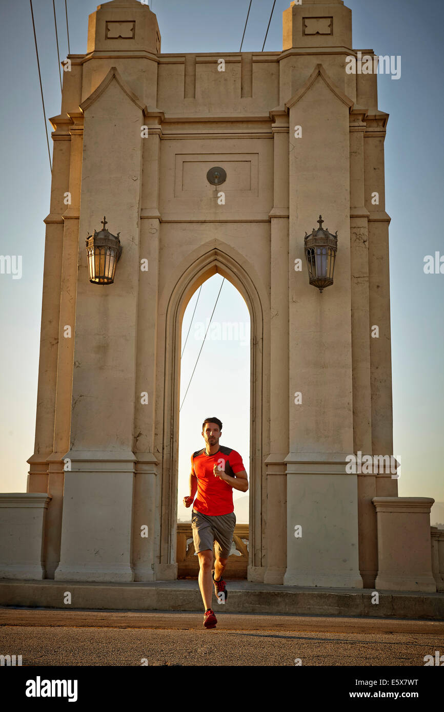 Young man running across city bridge Stock Photo - Alamy