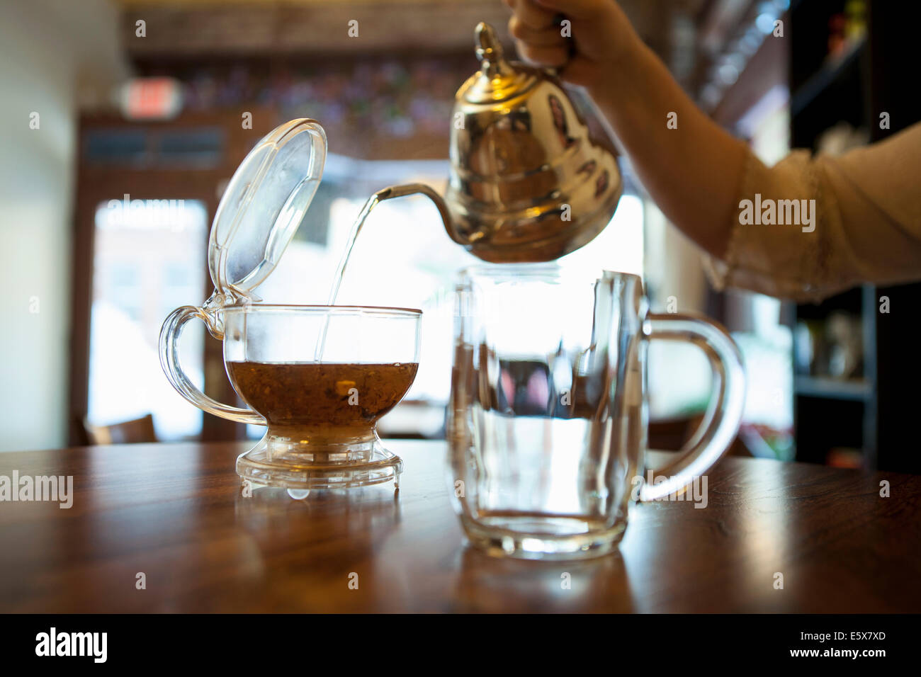 Female hand pouring tea on cafe counter Stock Photo - Alamy