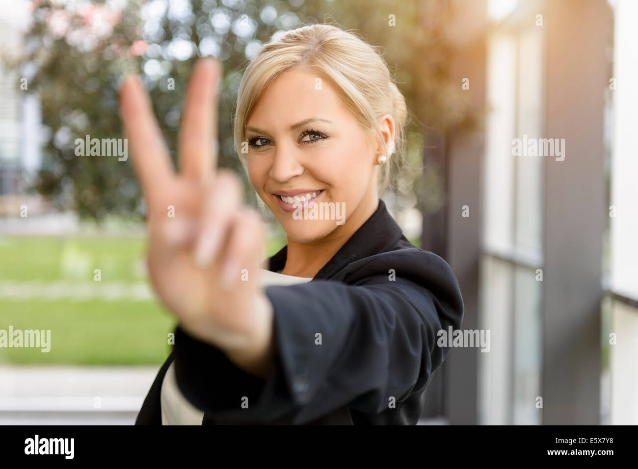 Portrait of young businesswoman making victory sign Stock Photo - Alamy