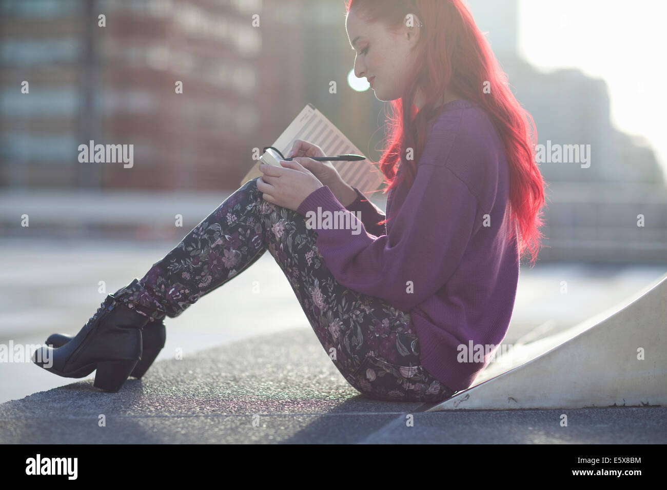Young woman writing in notebook on city rooftop parking lot Stock Photo ...