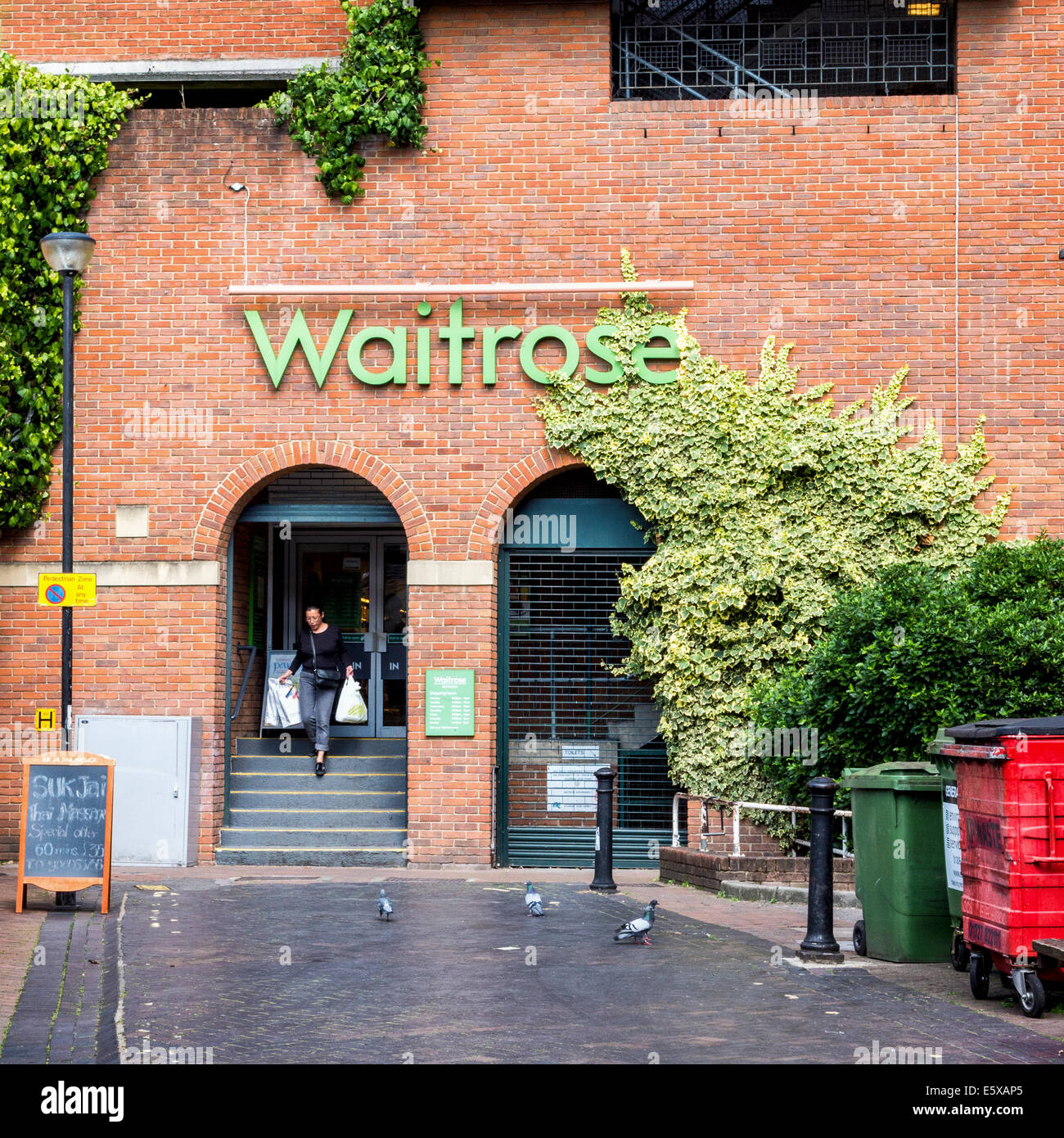 Waitrose Supermarket back entrance and woman with shopping bags ...