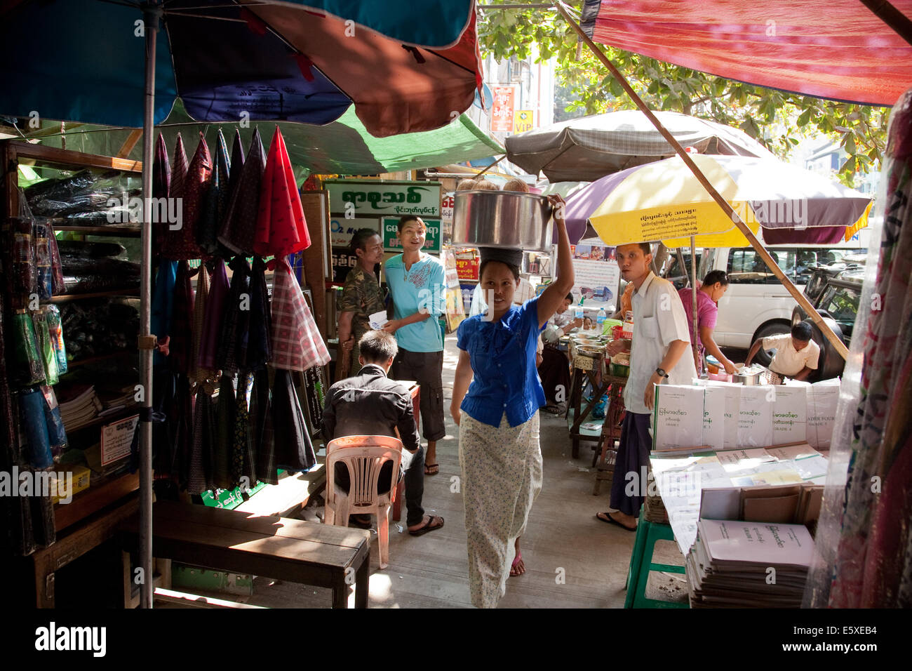 A woman walking through street stalls in central Yangon, Myanamar ...