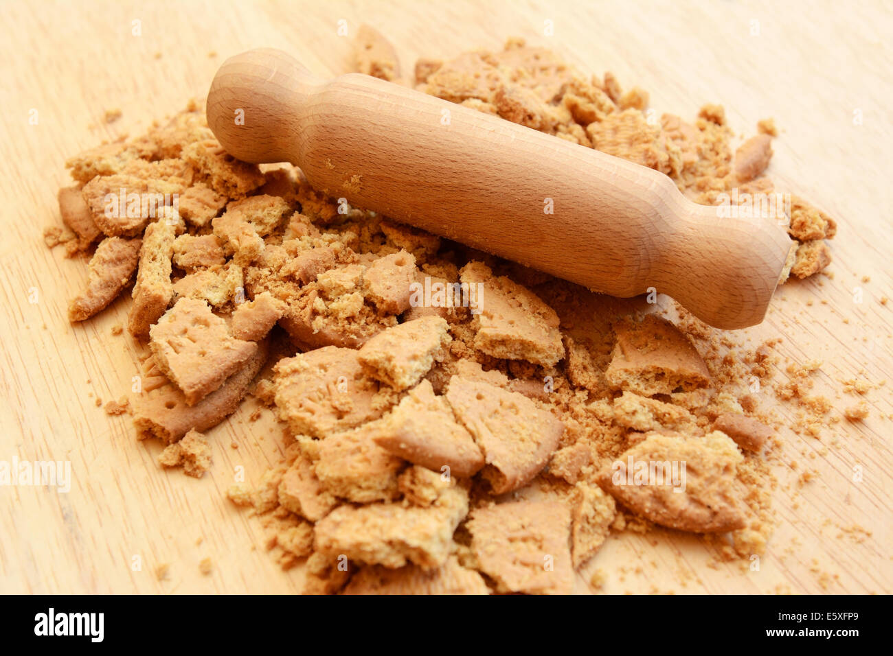 Crushing digestive biscuits into small pieces and crumbs with a wooden ...