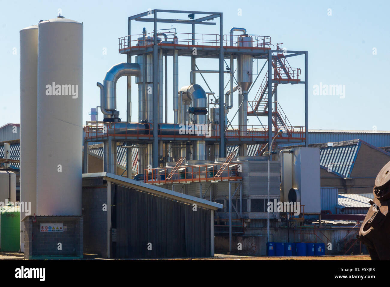 metal deposits and a small factory chimneys Stock Photo - Alamy