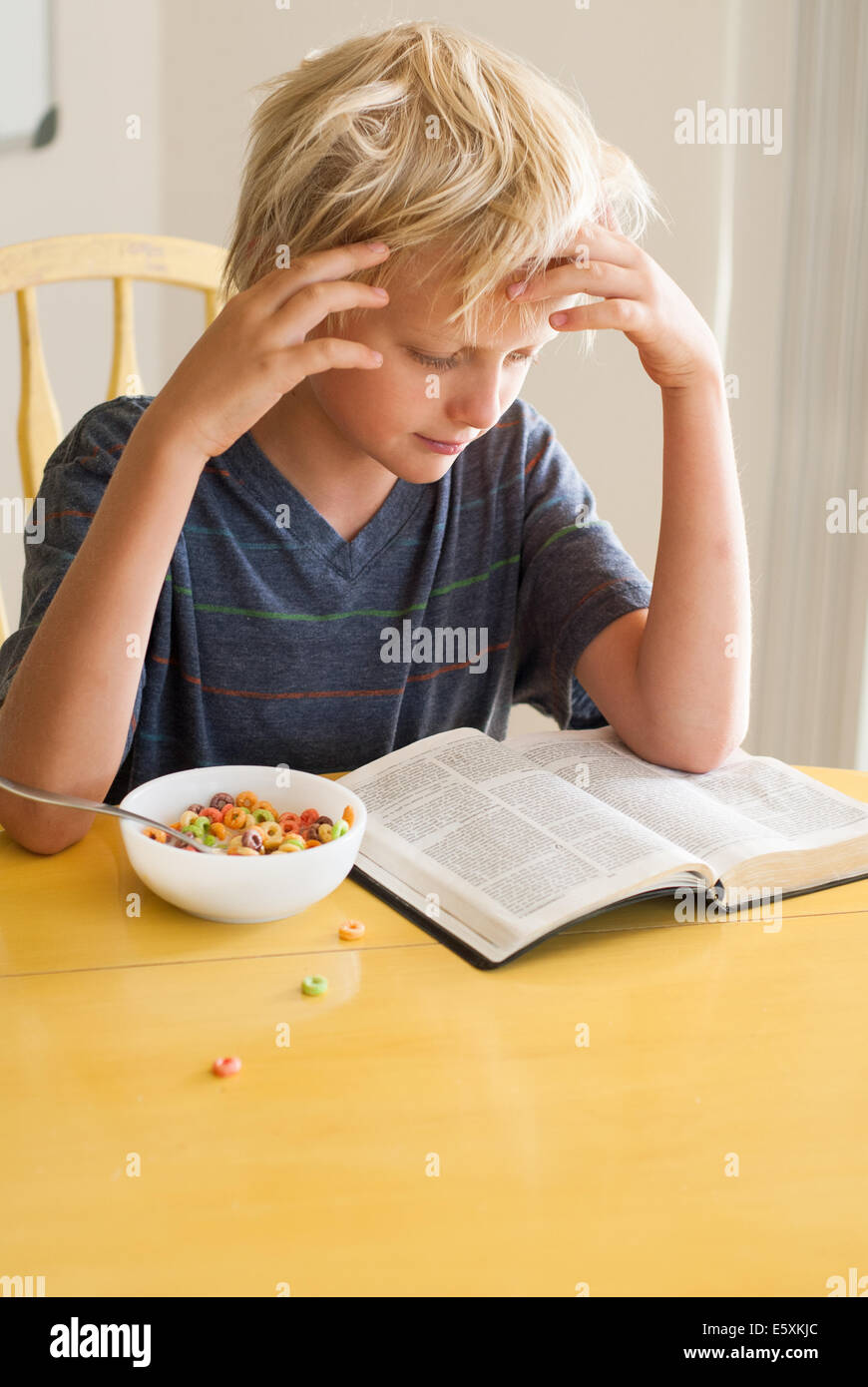 Young boy reading at breakfast Stock Photo - Alamy