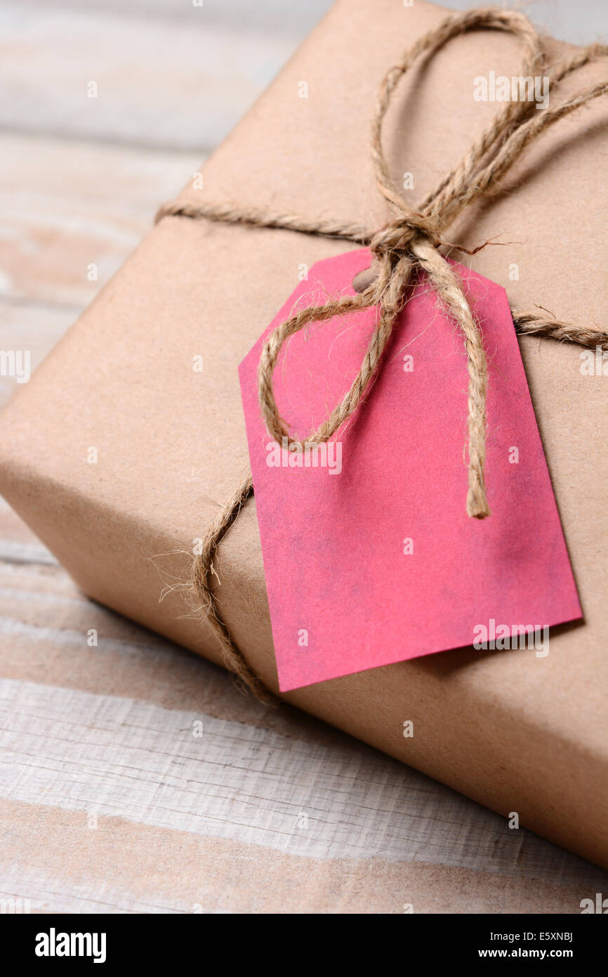 Closeup of a plain wrapped Christmas Present with a red gift tag. The ...