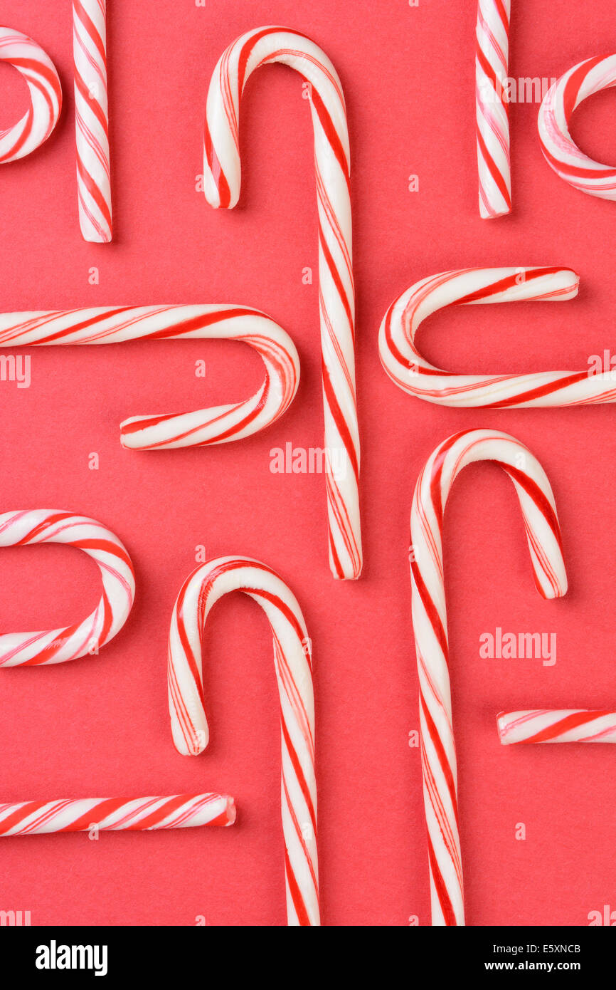 High angle shot of a group of Christmas candy canes on a red background ...