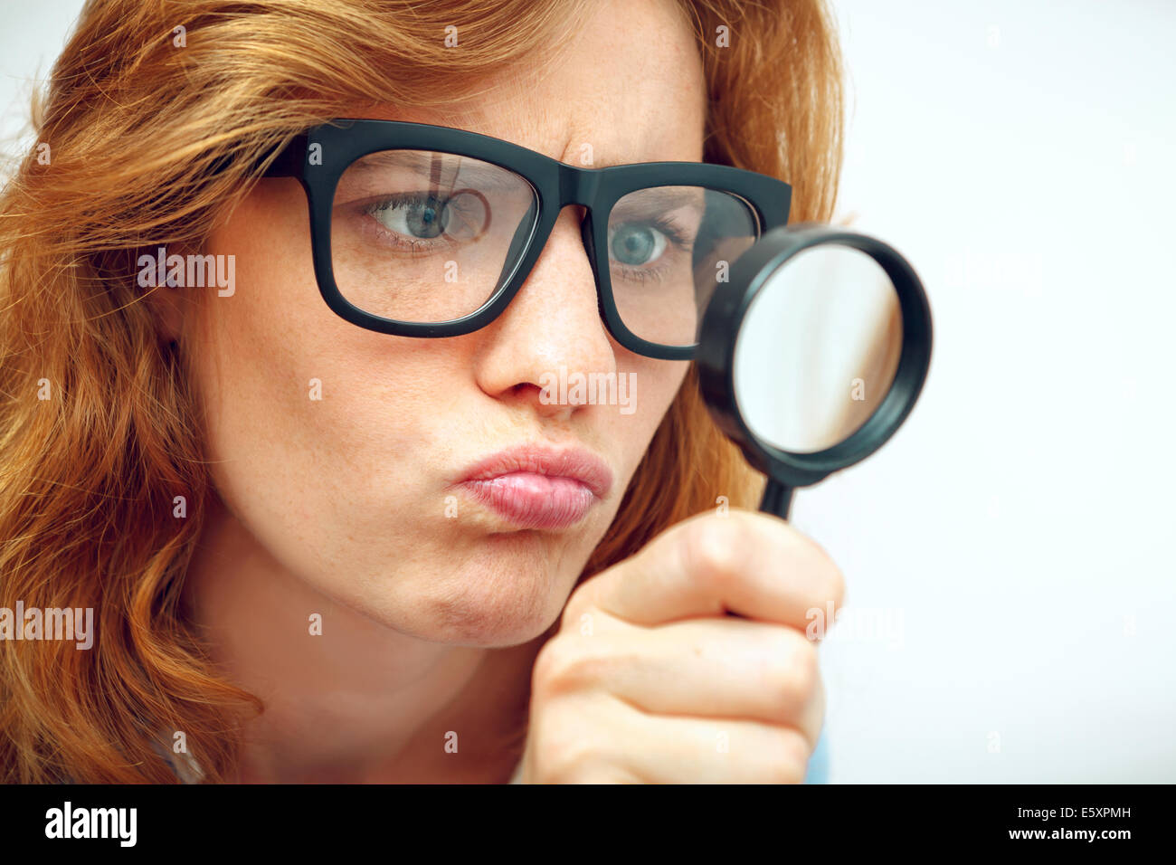 Young geek looking through magnifying glass Stock Photo - Alamy