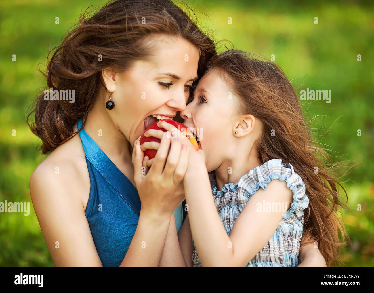 Mother and her child enjoy the early spring, eating apple, happy Stock ...