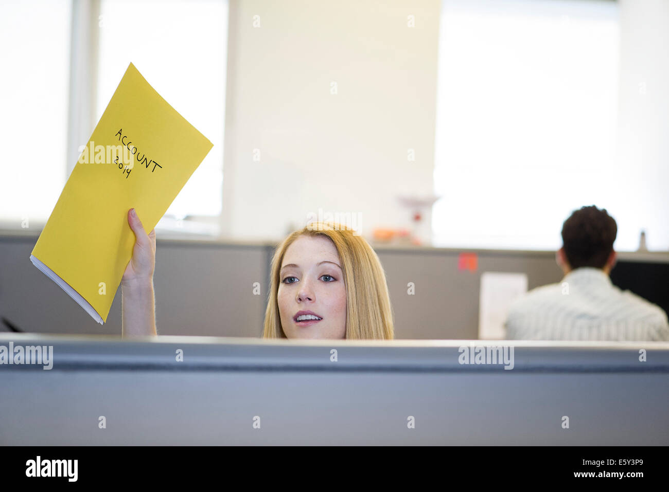 Accountant in office cubicle handing accounts file to out-of-frame ...