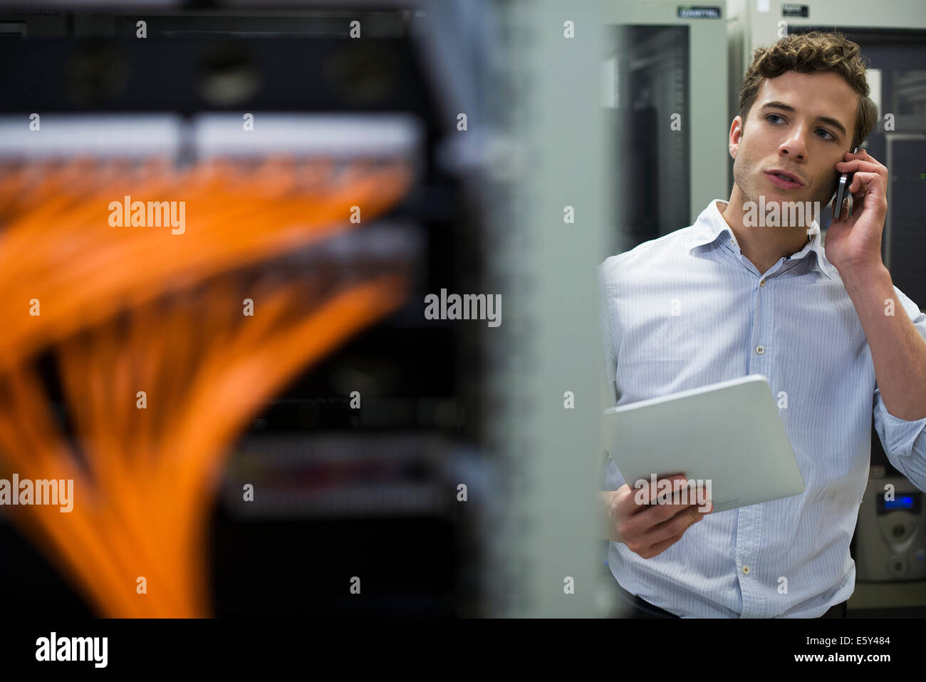Computer technician performing maintenance check of mainframe equipment ...