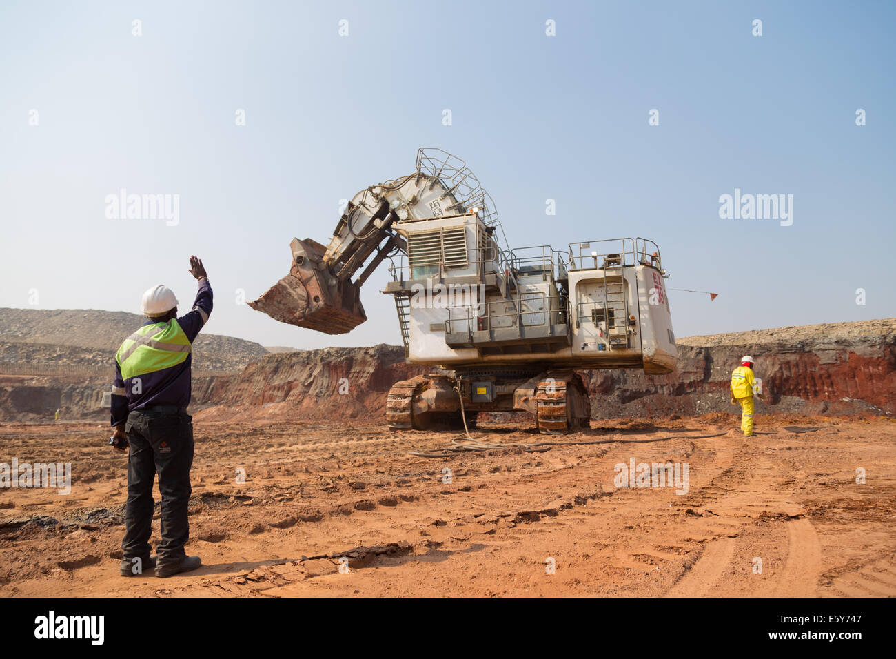 A supervisor guides and instructs an excavator operator during ...