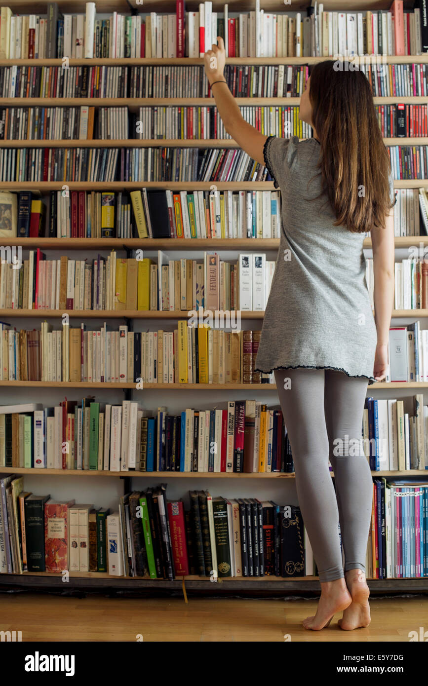 Woman selecting book from shelf, rear view Stock Photo - Alamy