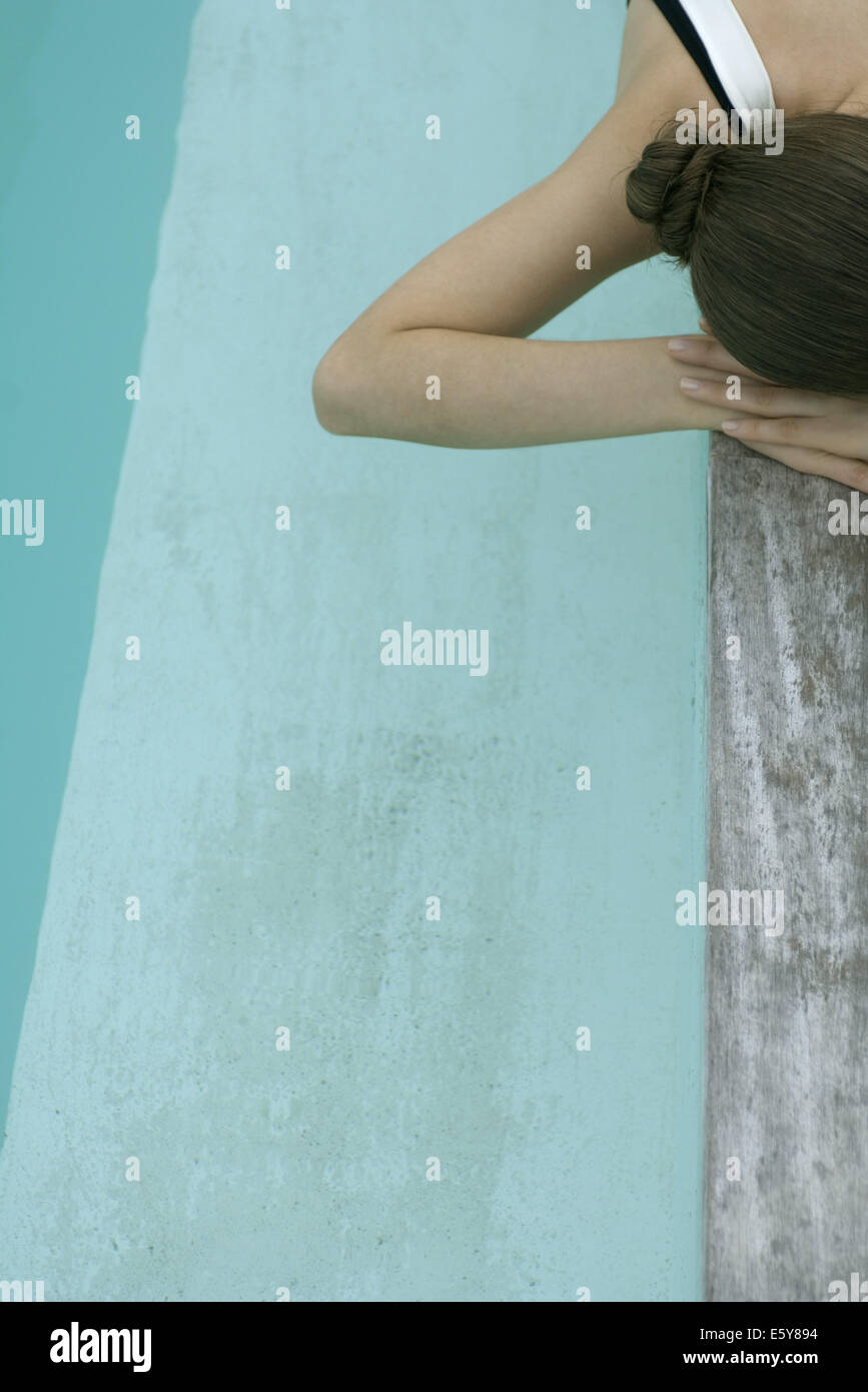 Woman lying on deck next to pool, resting head on arms Stock Photo - Alamy
