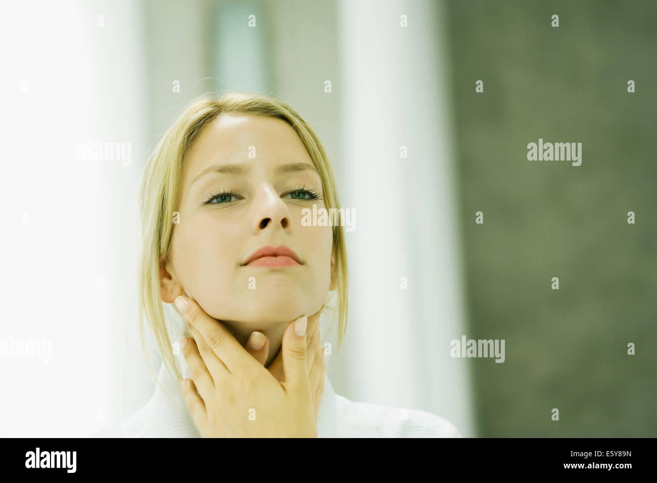 Woman touching her neck Stock Photo - Alamy
