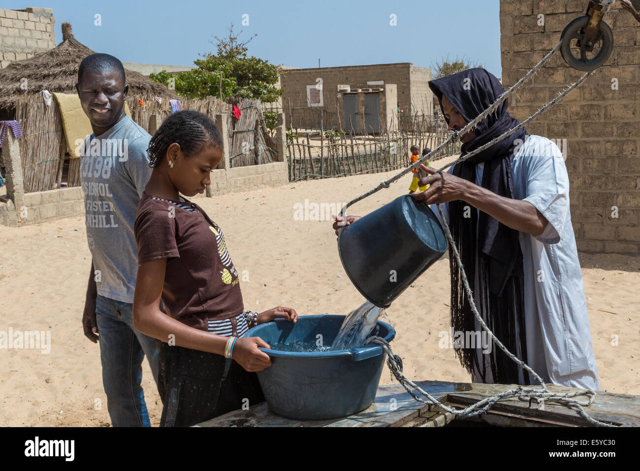 Man gathering water from the well with residents, Village of Peulh, aka ...
