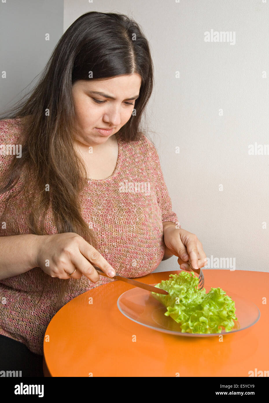 Stout woman trying to eat a leaf of lettuce Stock Photo - Alamy