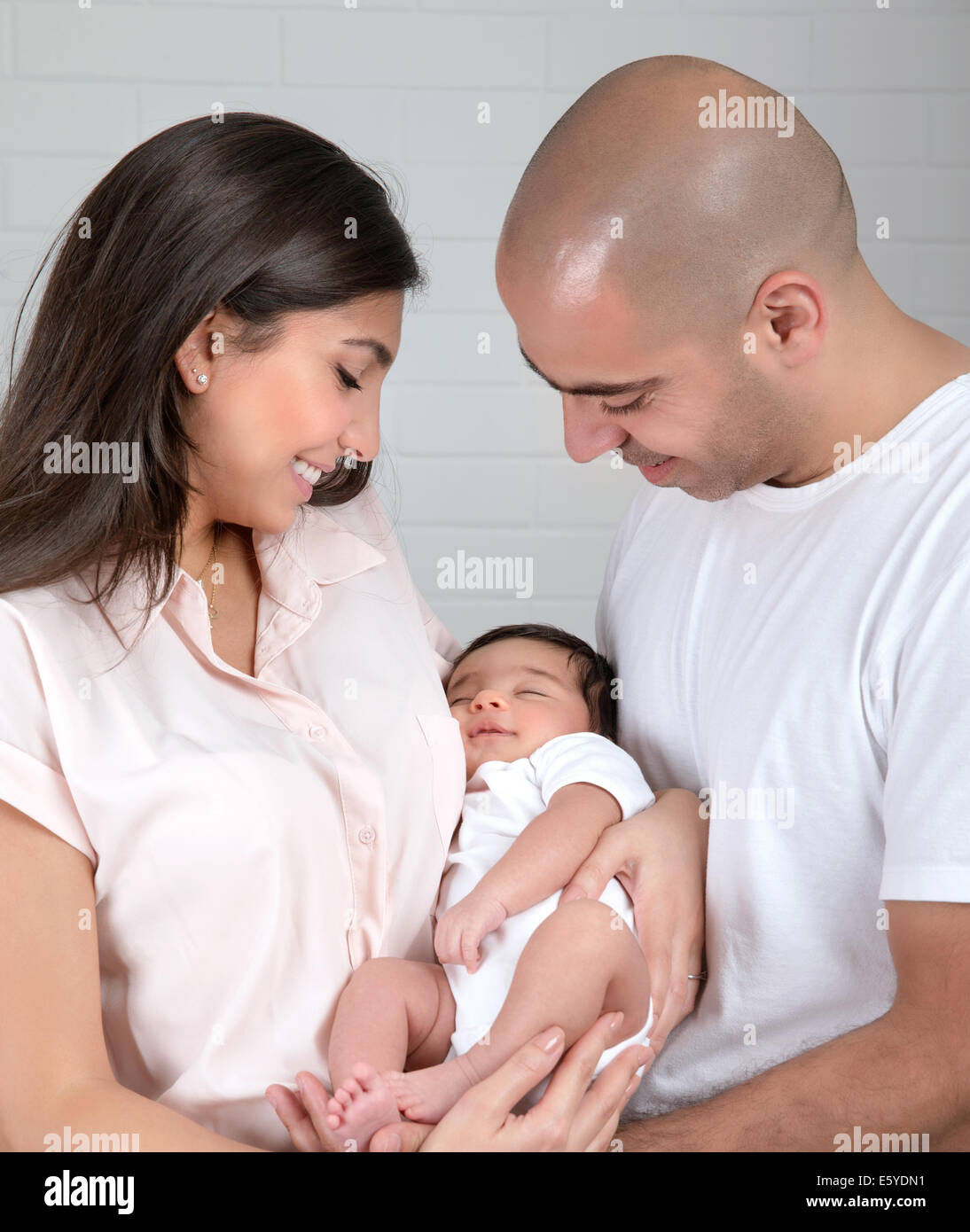 Portrait of cheerful young parents holding on hands cute newborn ...