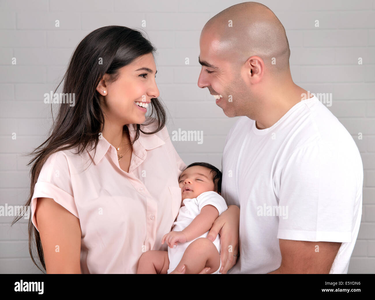 Portrait of cheerful young parents holding on hands cute newborn ...