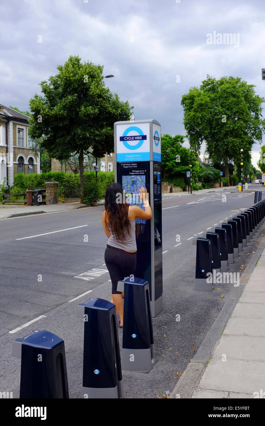 young woman looking at map empty cycle hire point in Haggerston, London ...