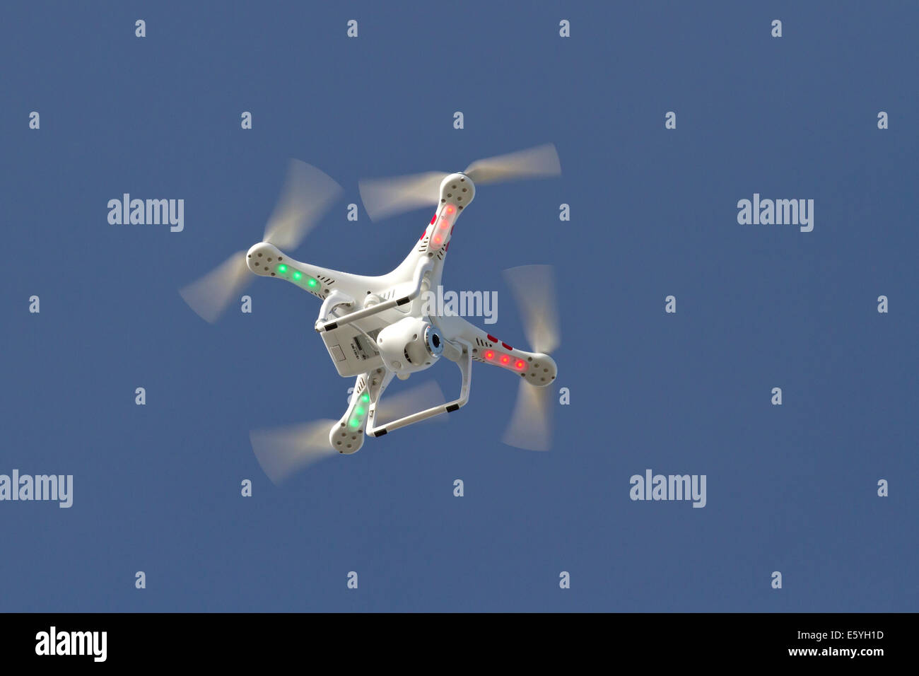 small unmanned helicopter with a camera floating in the blue sky ...