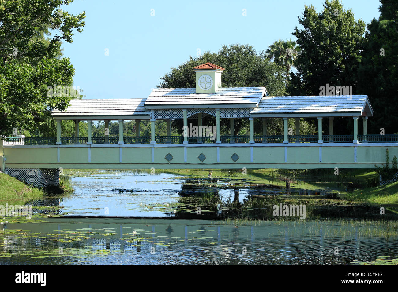 A covered bridge reflected in the water of a lake in Orlando, Florida ...
