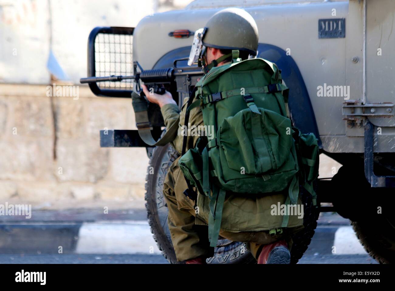 An Israeli soldiers crouches near a military jeep, armed with an M-16 ...