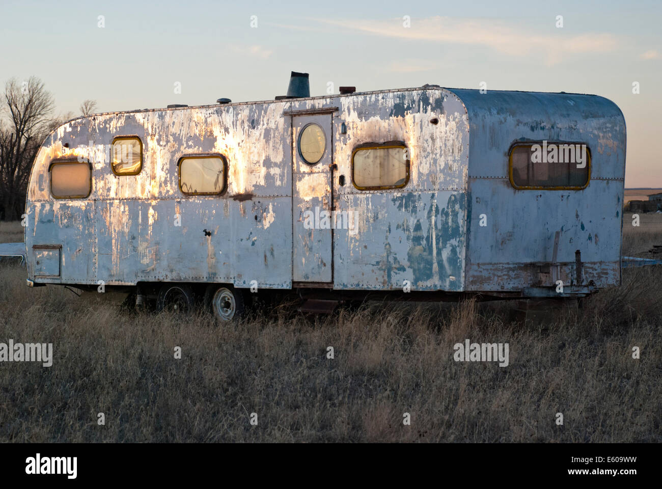 An old silver trailer reflects the afternoon sunlight in a field in ...