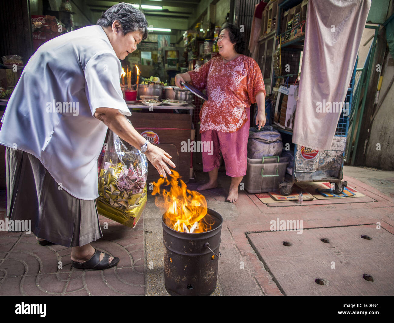 Bangkok, Thailand. 10th Aug, 2014. A woman burns joss paper and hell ...