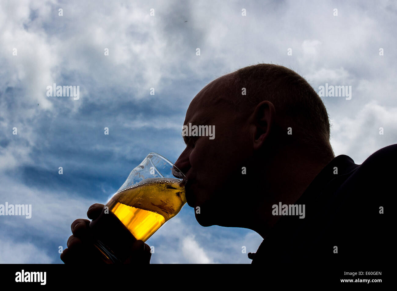 A man drinking a pint of real ale, silhouetted against a blue sky Stock ...