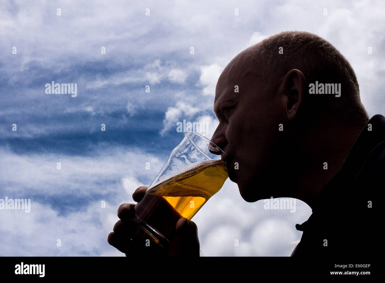 A man drinking a pint of real ale, silhouetted against a blue sky Stock ...
