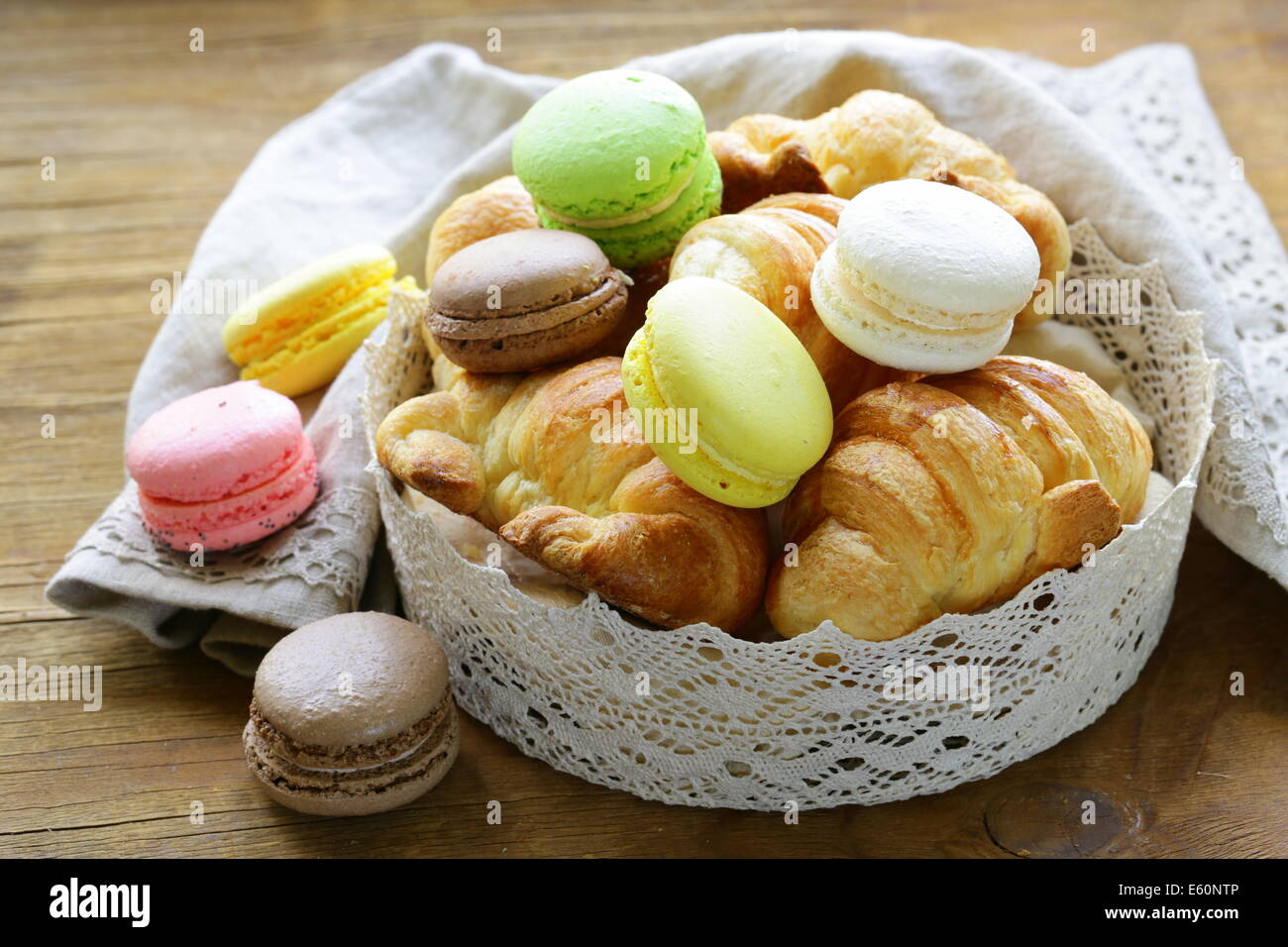 traditional French pastries croissants and macaroons in a lace basket ...