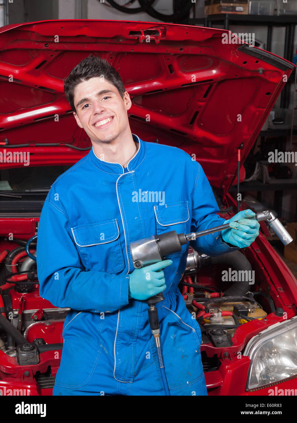 Mechanical smiling and holding a tool in a garage Stock Photo - Alamy