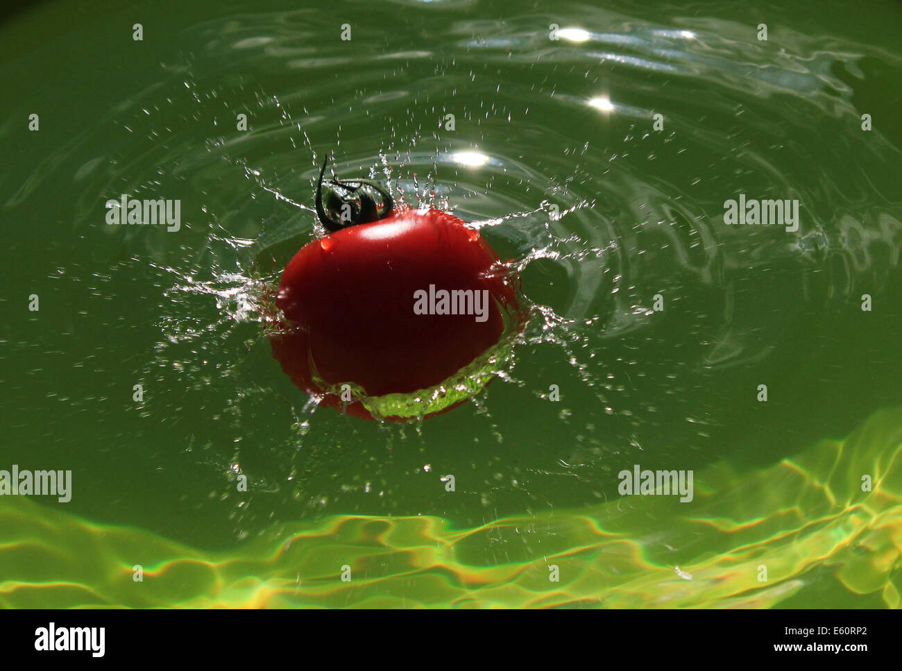 Tomato dropping into bowl of water Stock Photo - Alamy