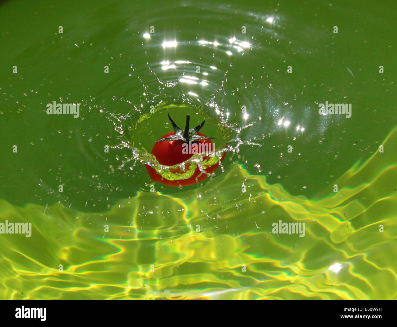 Tomato dropping into bowl of water Stock Photo - Alamy