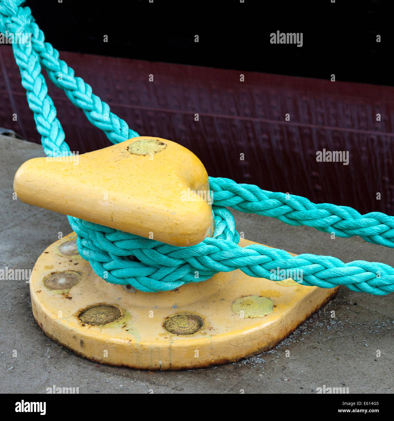 Yellow mooring bollard with green ropes Stock Photo - Alamy